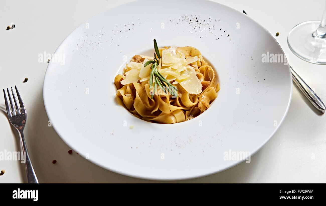 Close-up italian pasta plate with grated parmesan cheese and basil leaf ...