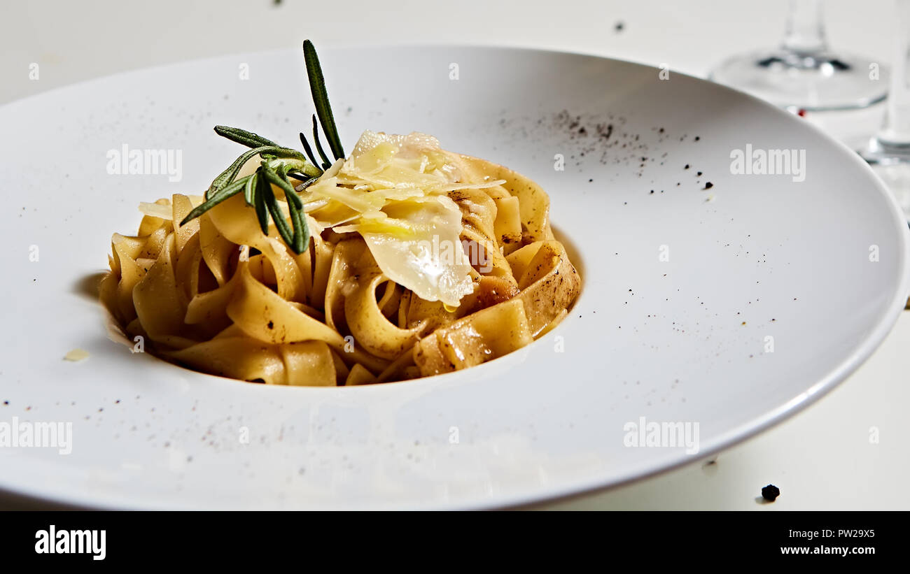 Close-up italian pasta plate with grated parmesan cheese and basil leaf ...