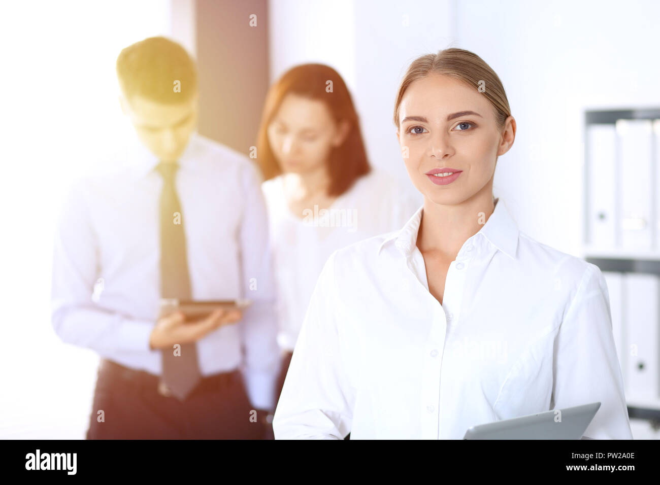 Beautiful blonde businesswoman standing straight in a brightly lit ...