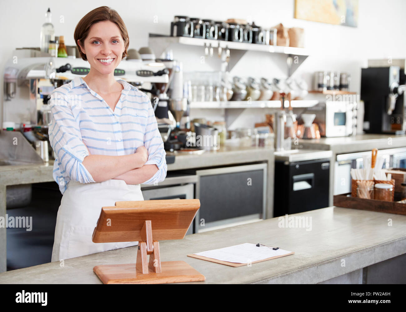 Smiling woman behind counter at a coffee shop, arms crossed Stock Photo ...
