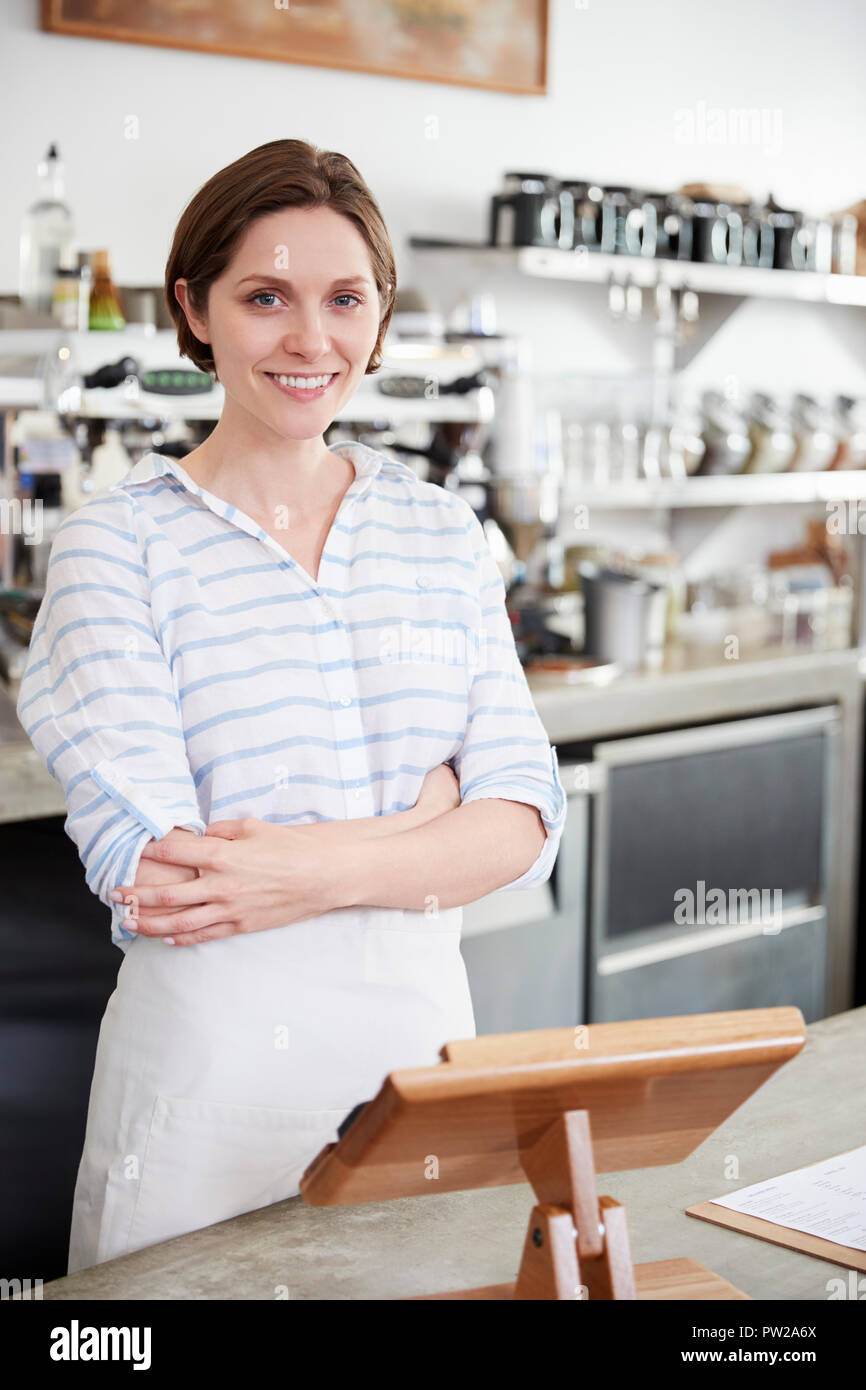 Young smiling woman behind counter at coffee shop, vertical Stock Photo ...