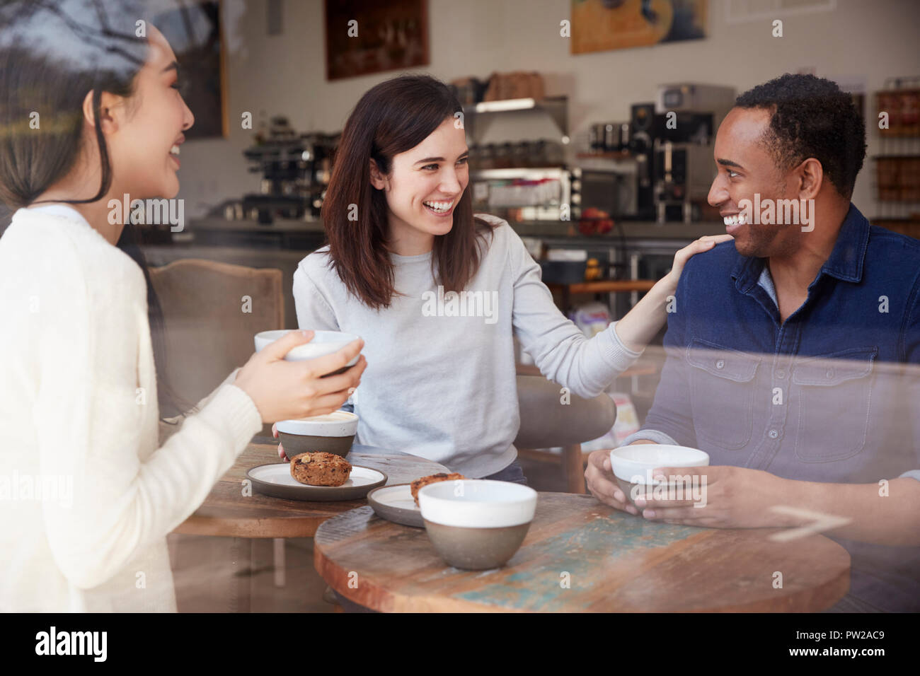 Three friends having coffee and laughing at a coffee shop Stock Photo ...