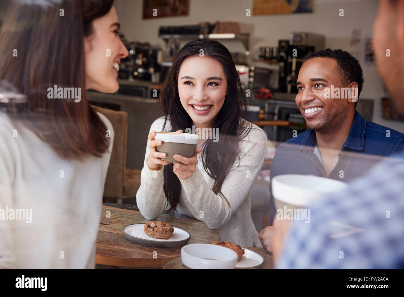 Four smiling friends having coffee at coffee shop, close up Stock Photo ...