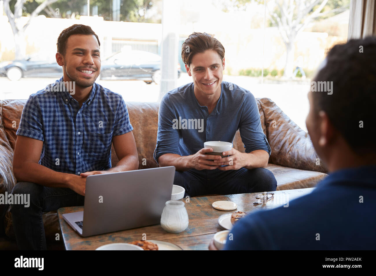 Three male friends talking over coffee at a coffee shop Stock Photo - Alamy