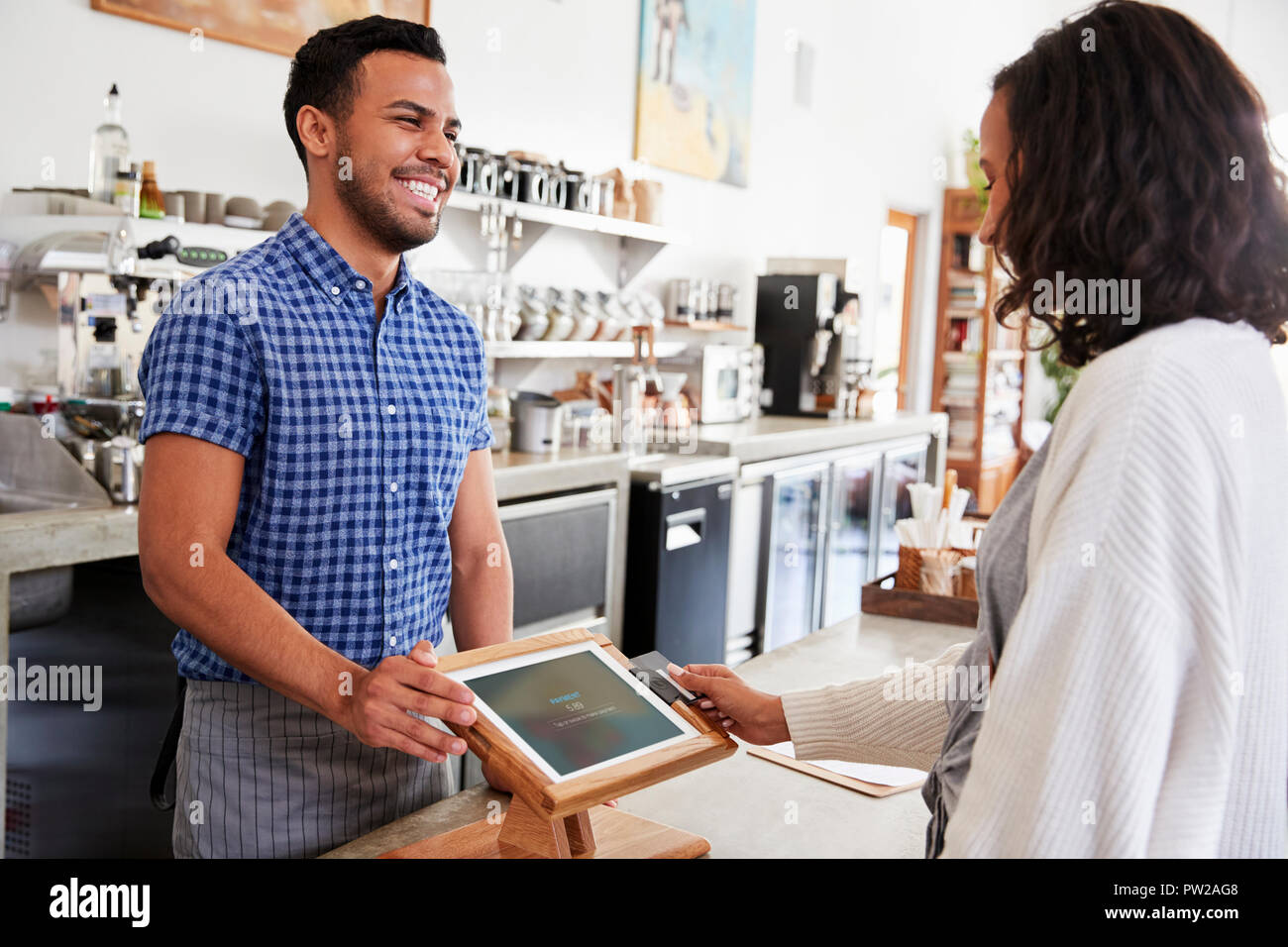 Male barista smiles at a female customer in a coffee shop Stock Photo ...