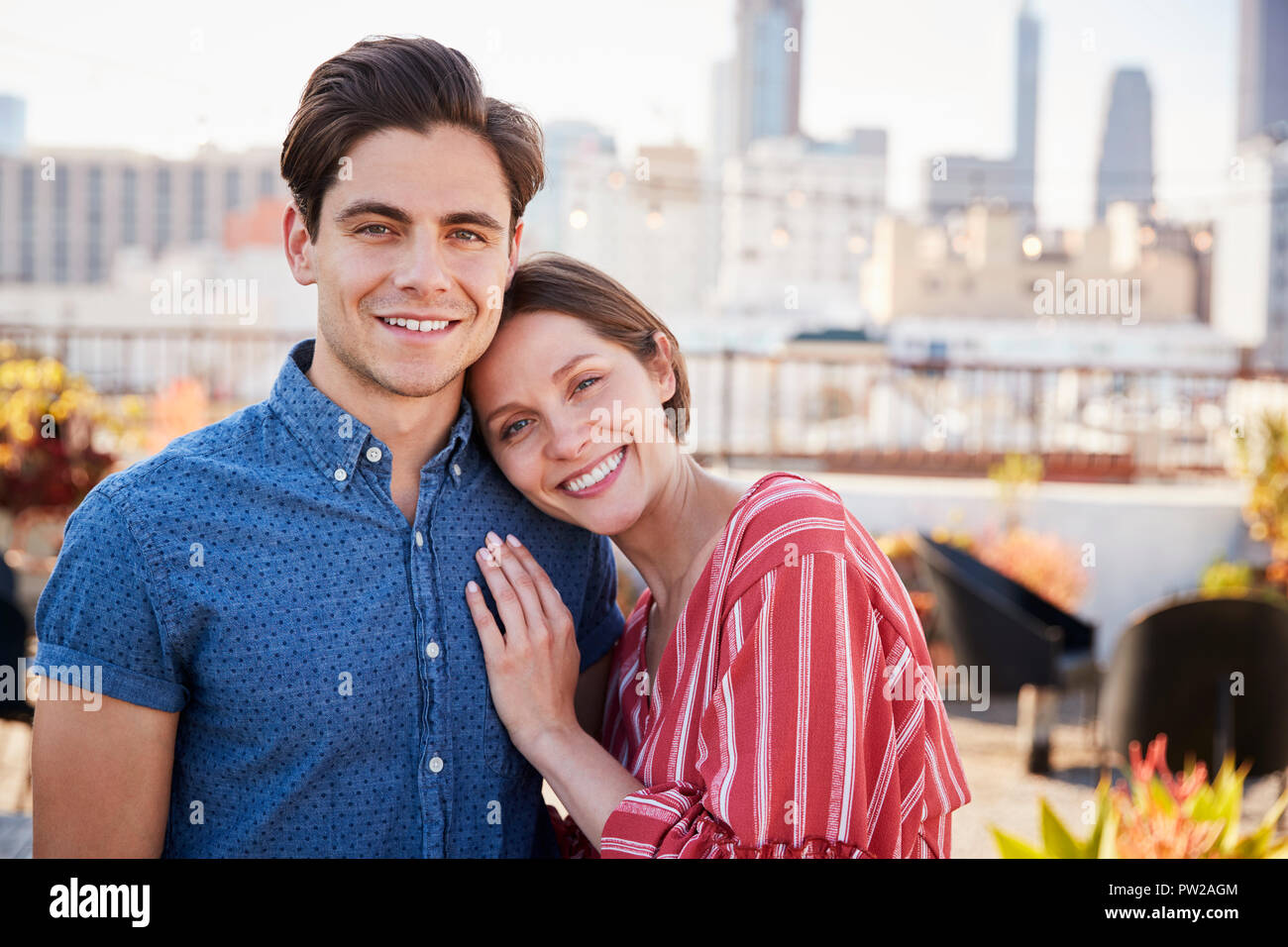 Portrait Of Romantic Couple On Rooftop Terrace With City Skyline In ...