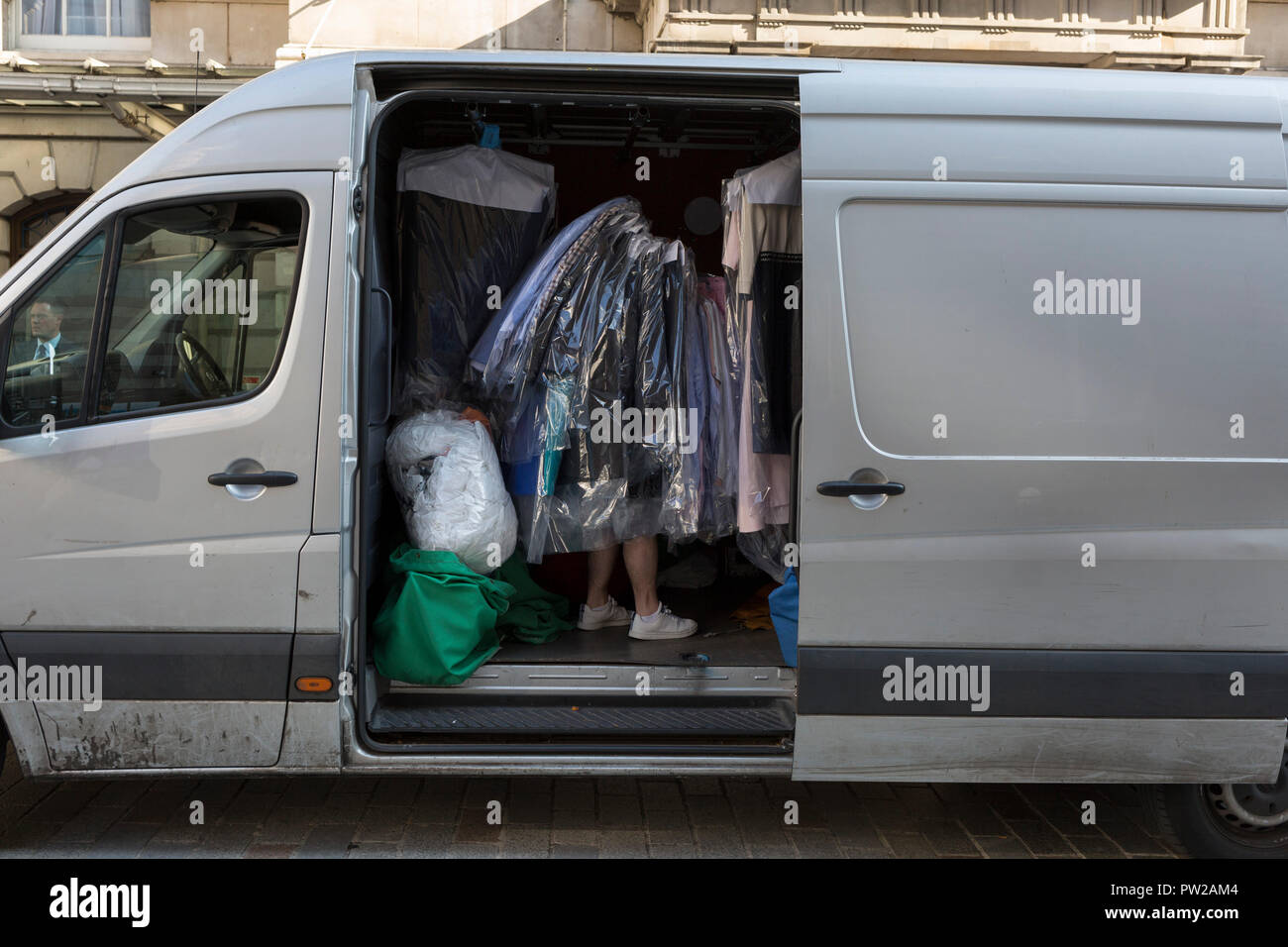 Emerging from his van, a dry cleaning contractor gathers many items of ...