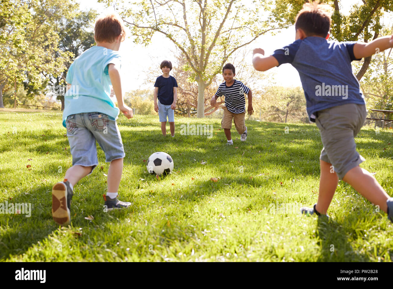 Four young schoolboys playing football together in the park Stock Photo ...