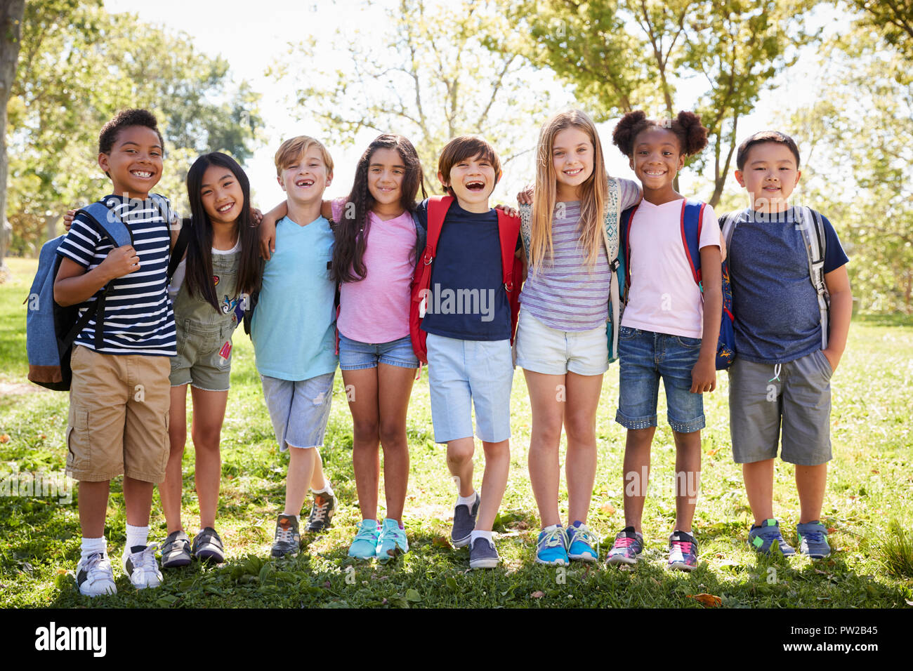 School kids stand embracing in a row outdoors, full length Stock Photo ...