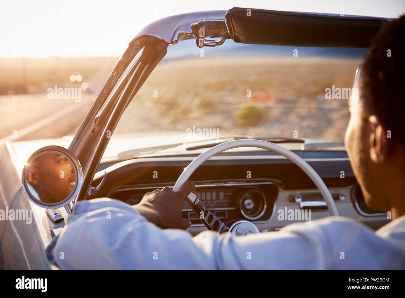 Rear View Of Man On Road Trip Driving Classic Convertible Car Towards ...