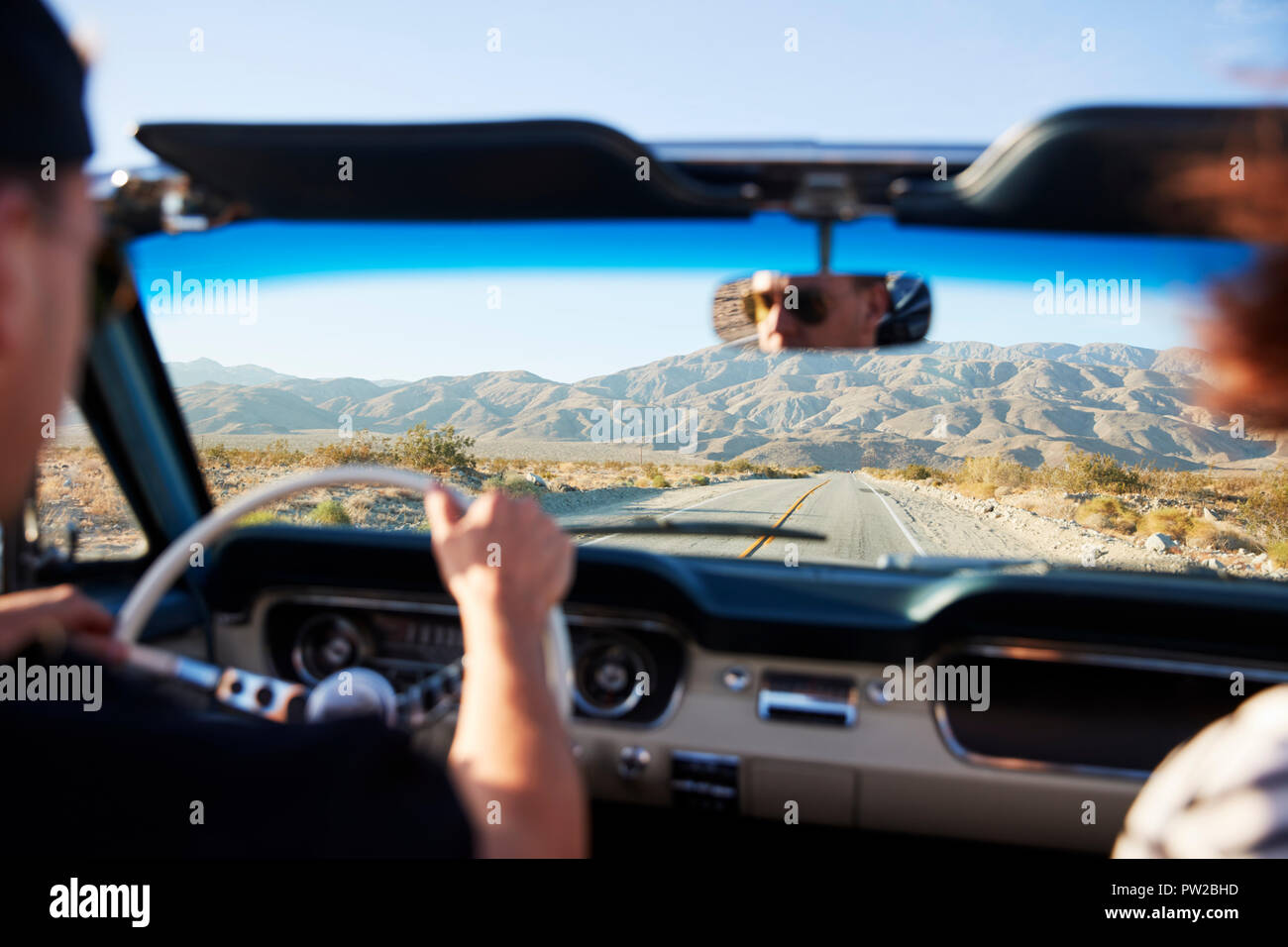 Rear View Of Man On Road Trip Driving Classic Convertible Car Towards ...