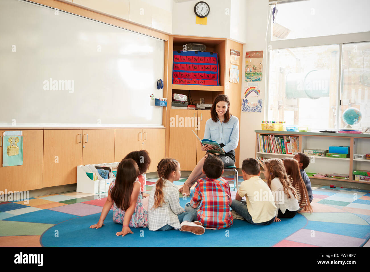 Kids sitting around teacher hi-res stock photography and images - Alamy