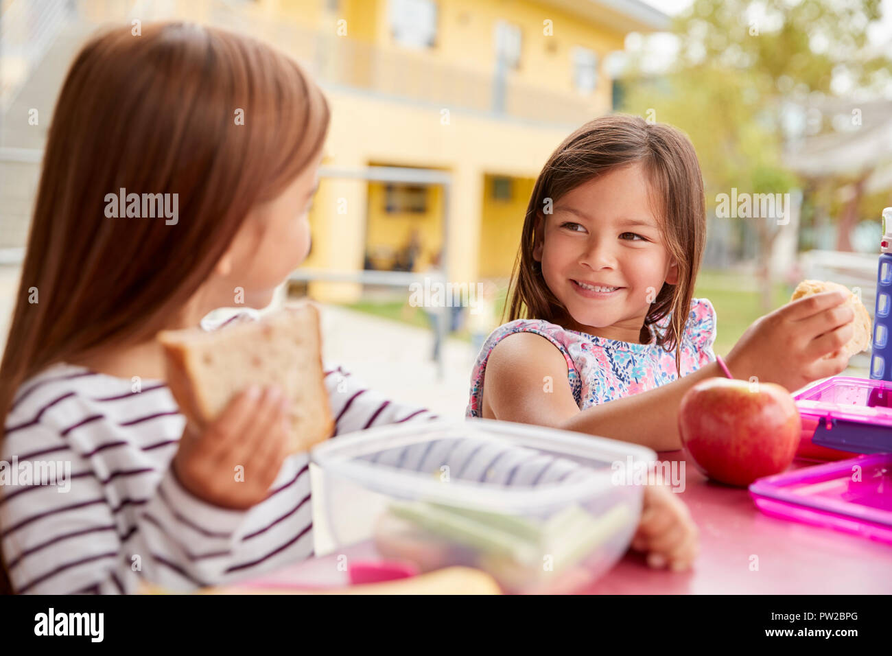 Two young schoolgirls eating packed lunch looking each other Stock ...