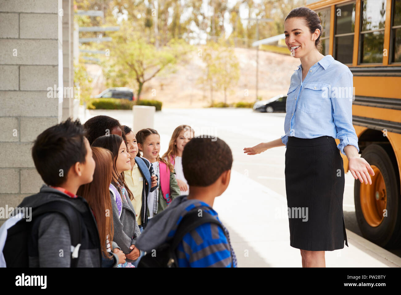 School teacher talking to kids before they get on school bus Stock ...