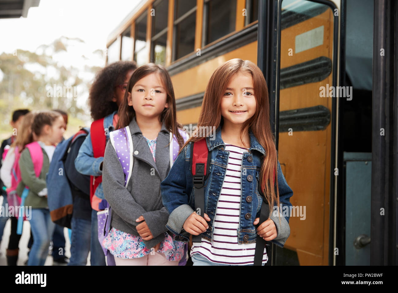 Two girls at the front of the elementary school bus queue Stock Photo ...