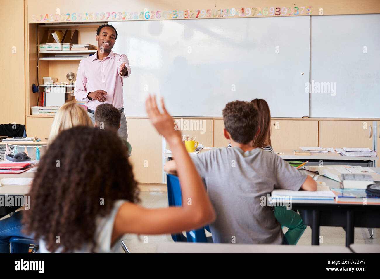 Teacher pointing to girl with hand raised in school class Stock Photo ...