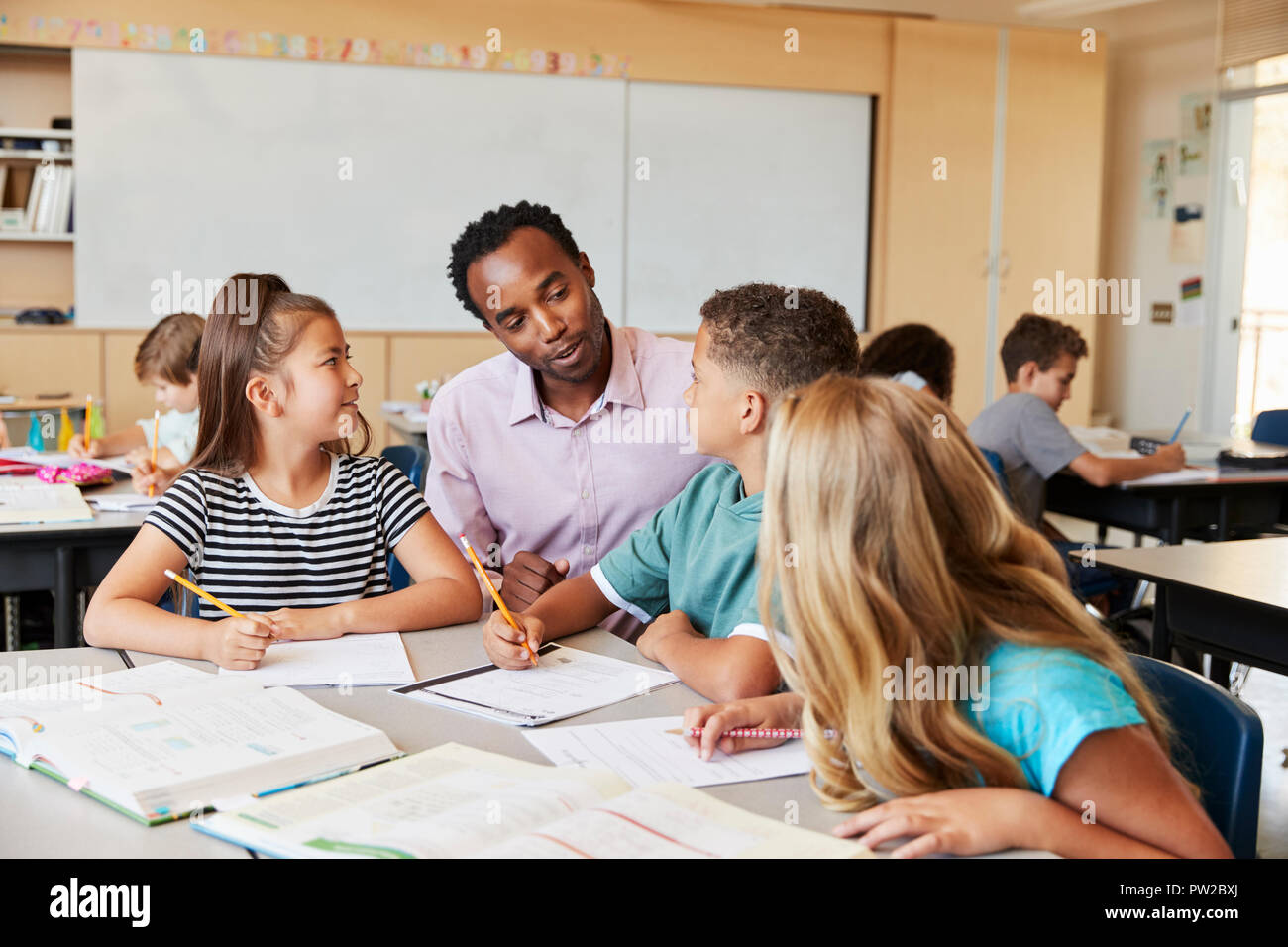 Teacher working with elementary school kids at their desk Stock Photo ...