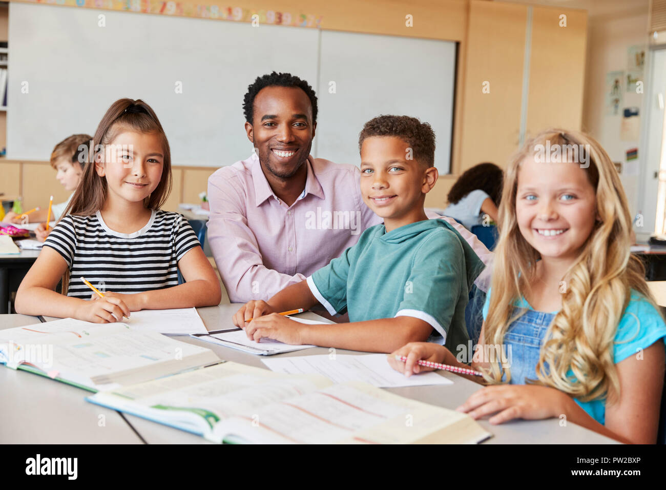 Male school teacher and kids in class smiling to camera Stock Photo - Alamy