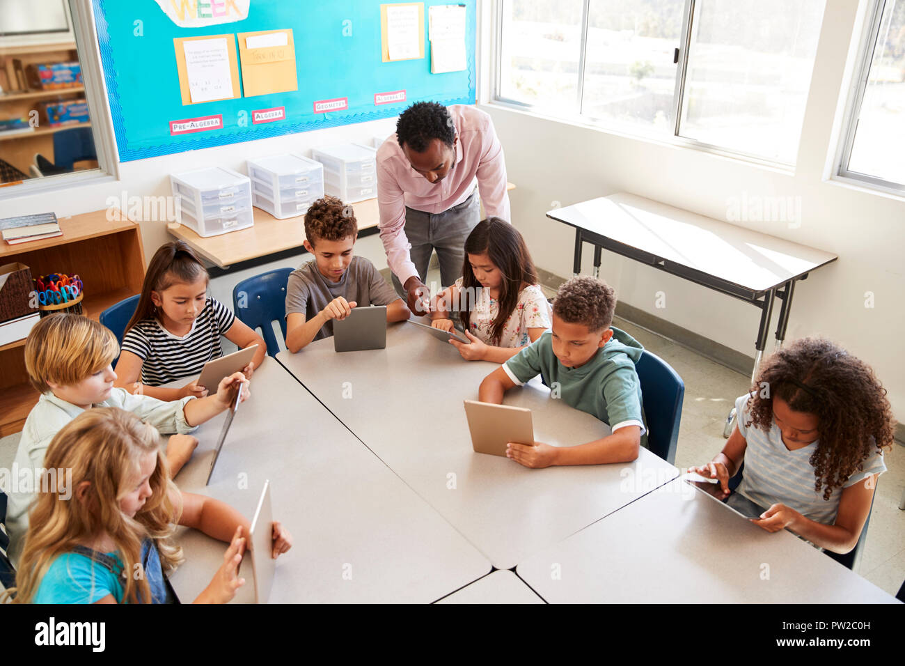 Teacher helping kids using tablets in lesson, elevated view Stock Photo ...
