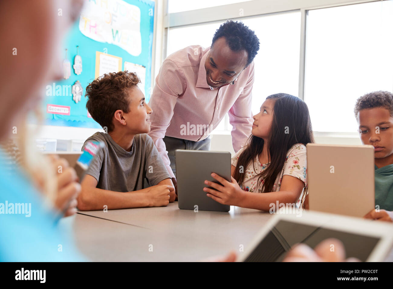 Teacher among kids with computers in elementary school class Stock ...