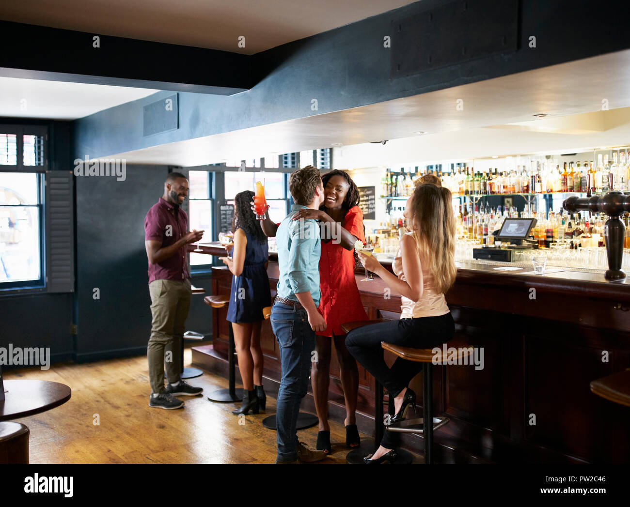 Group Of Young Friends Relaxing In Bar Standing At Counter Stock Photo ...