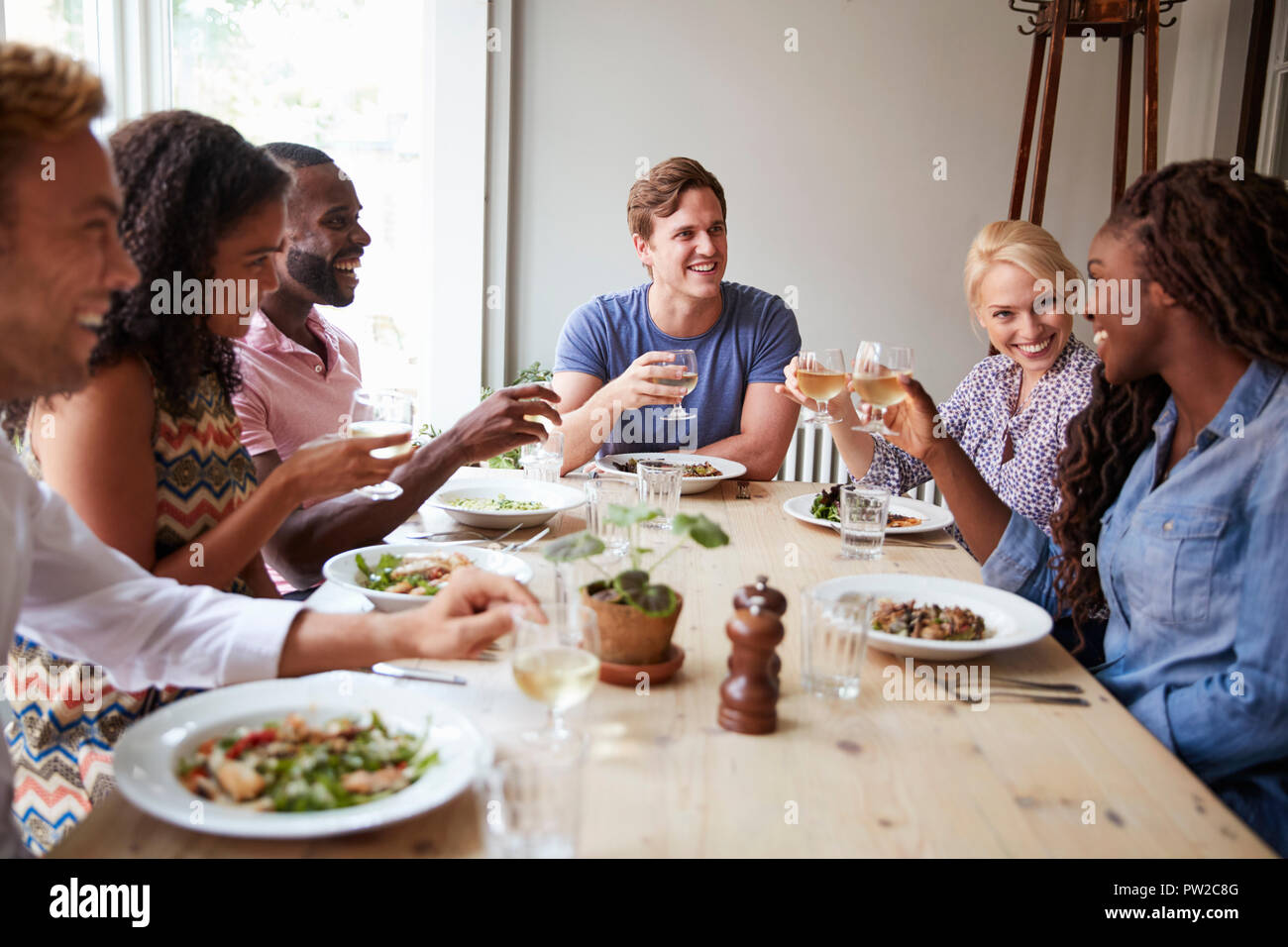 Friends Sitting At Table In Restaurant Making Toast Together Stock ...
