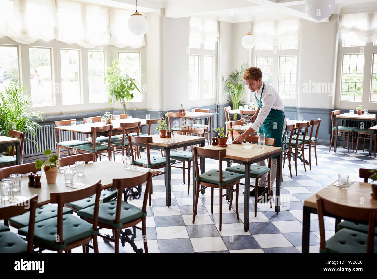 Waiter Laying Tables In Empty Restaurant Stock Photo - Alamy
