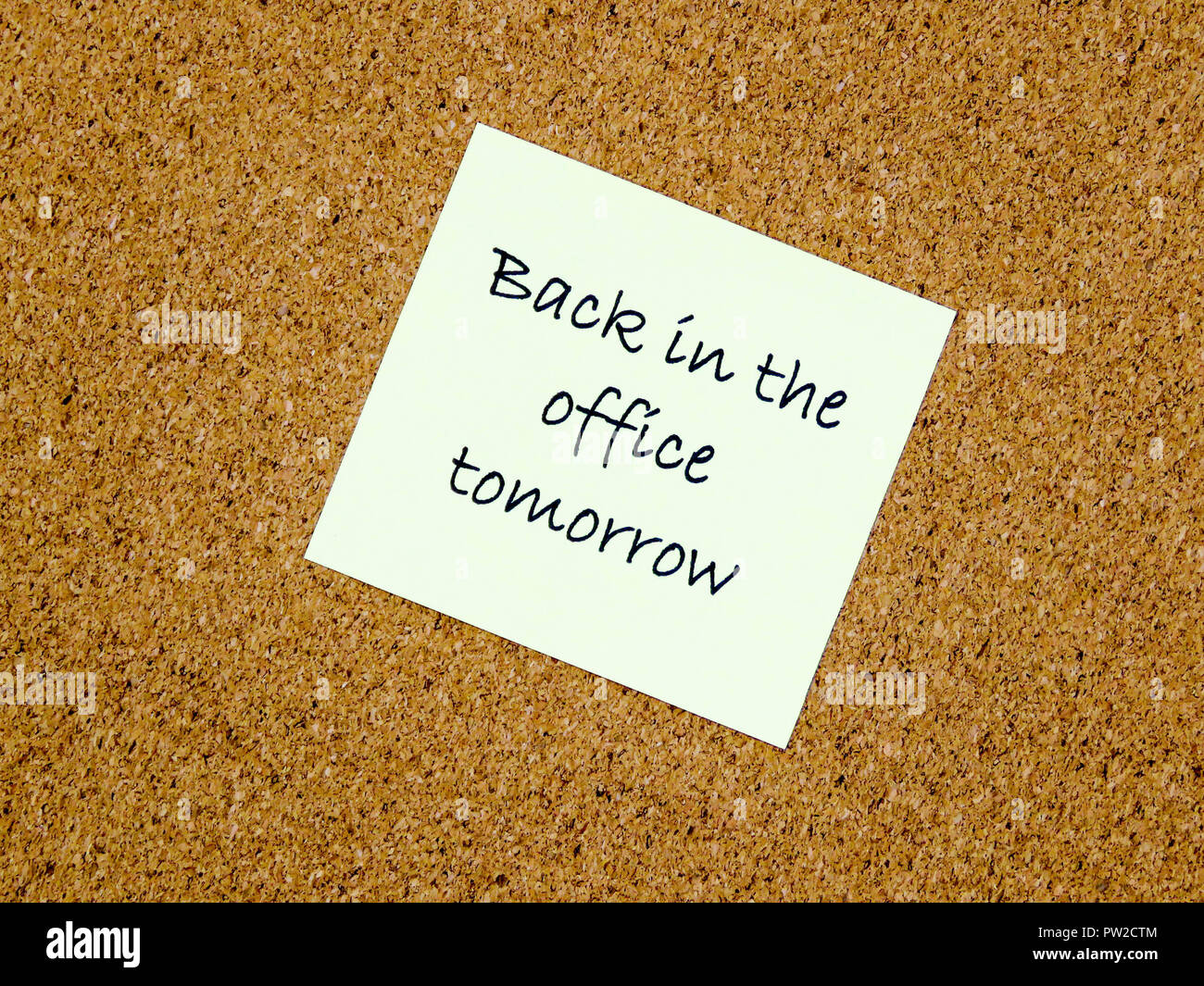 A yellow sticky note with back in the office tomorrow written on it on ...
