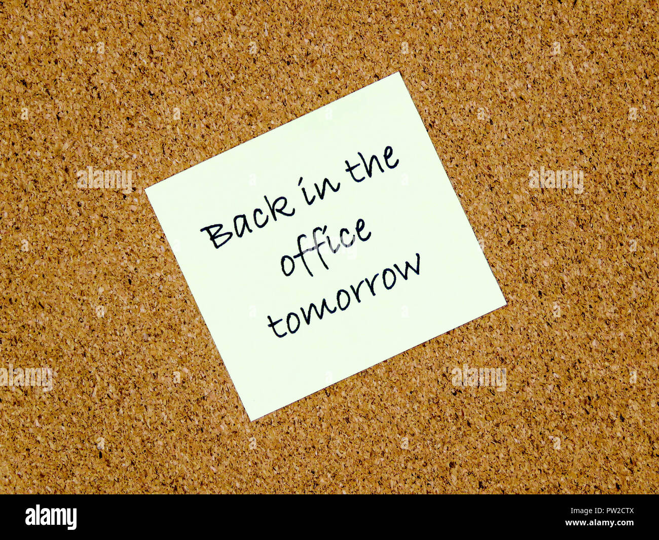 A yellow sticky note with back in the office tomorrow written on it on ...