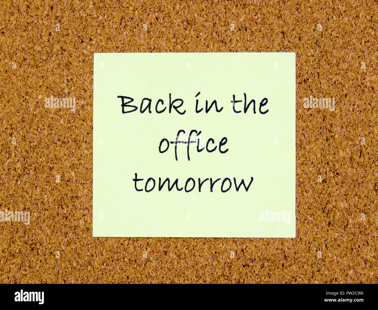 A yellow sticky note with back in the office tomorrow written on it on ...