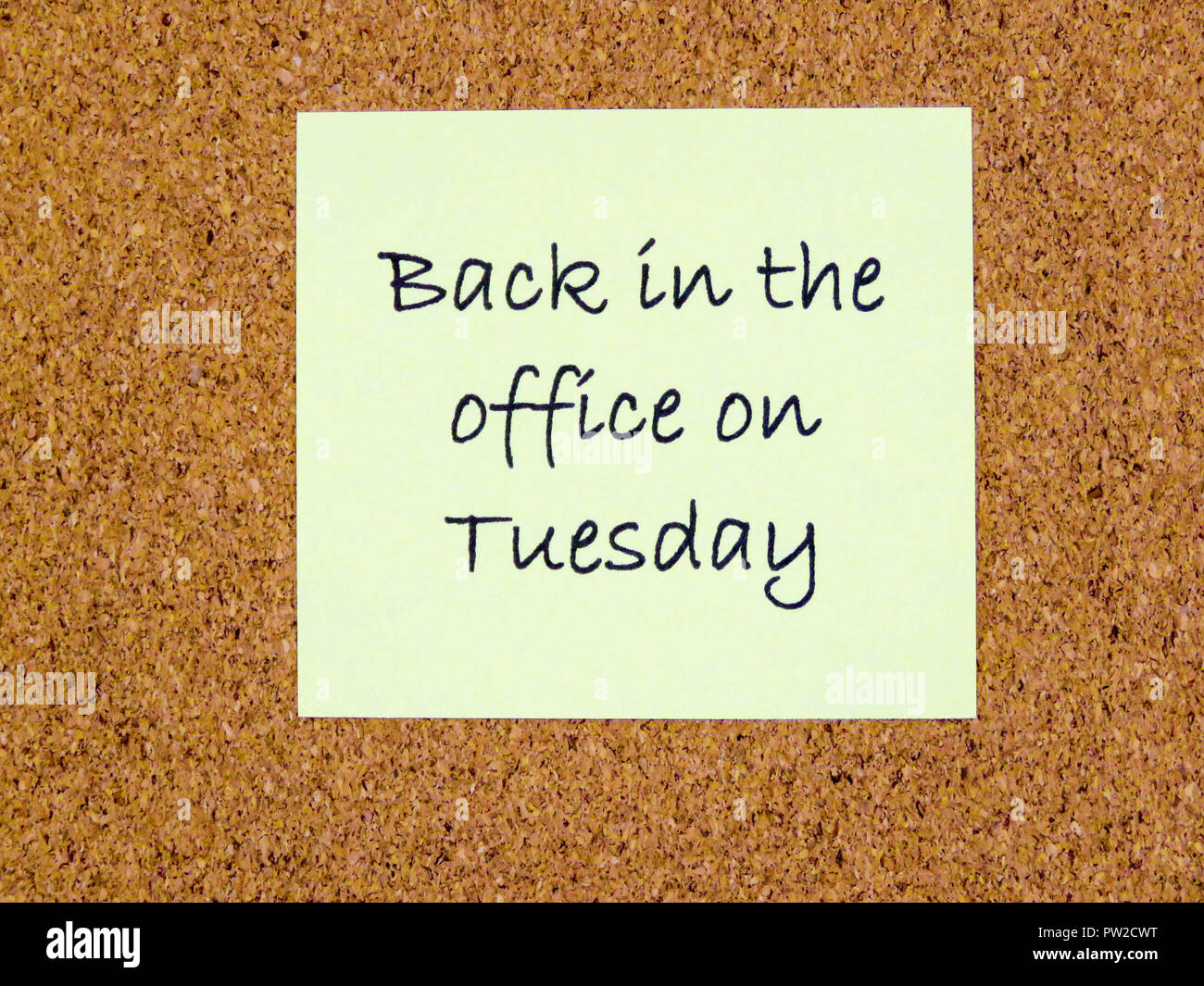 A yellow sticky note with back in the office on Tuesday written on it ...