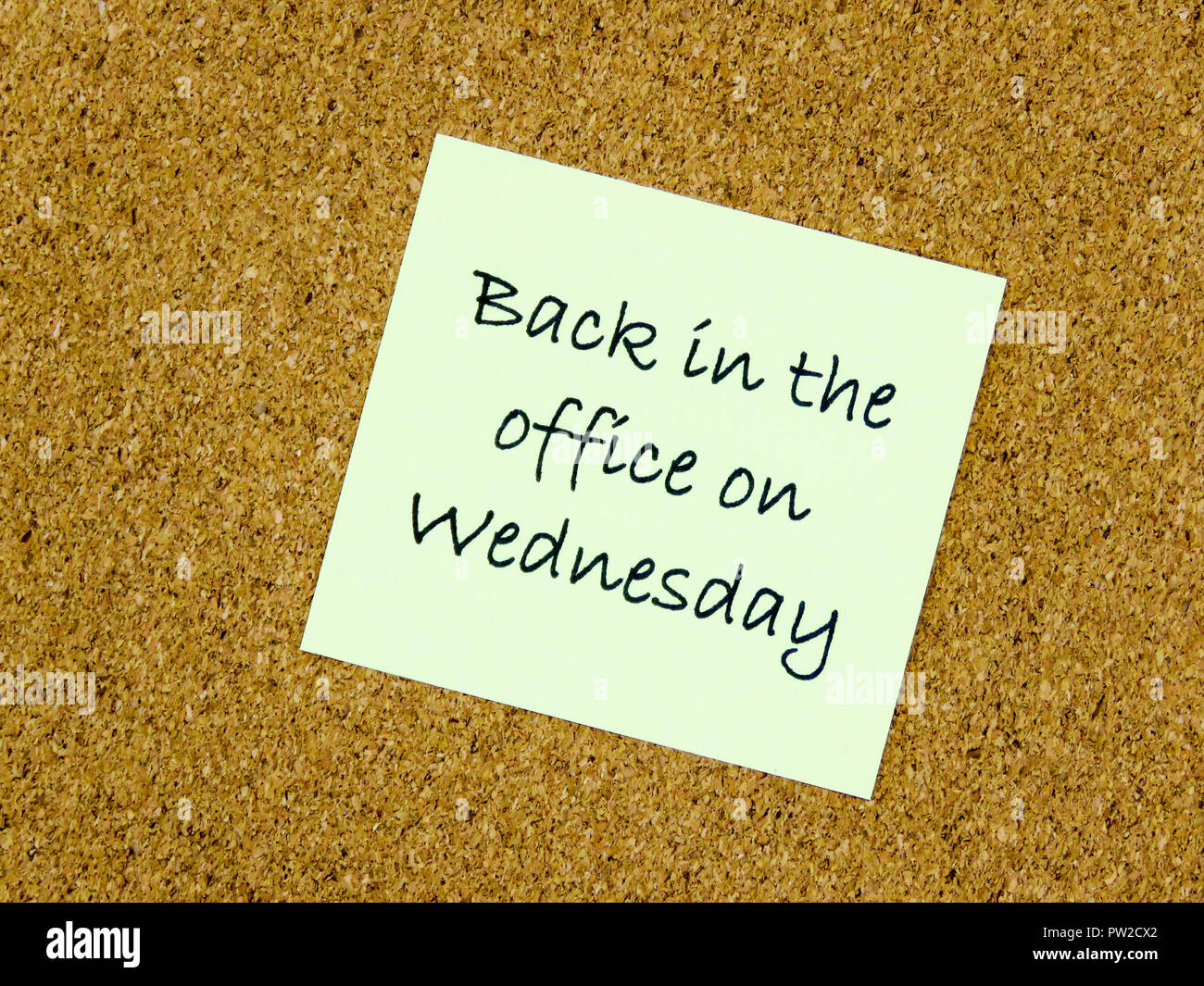 A yellow sticky note with back in the office on Wednesday written on it ...