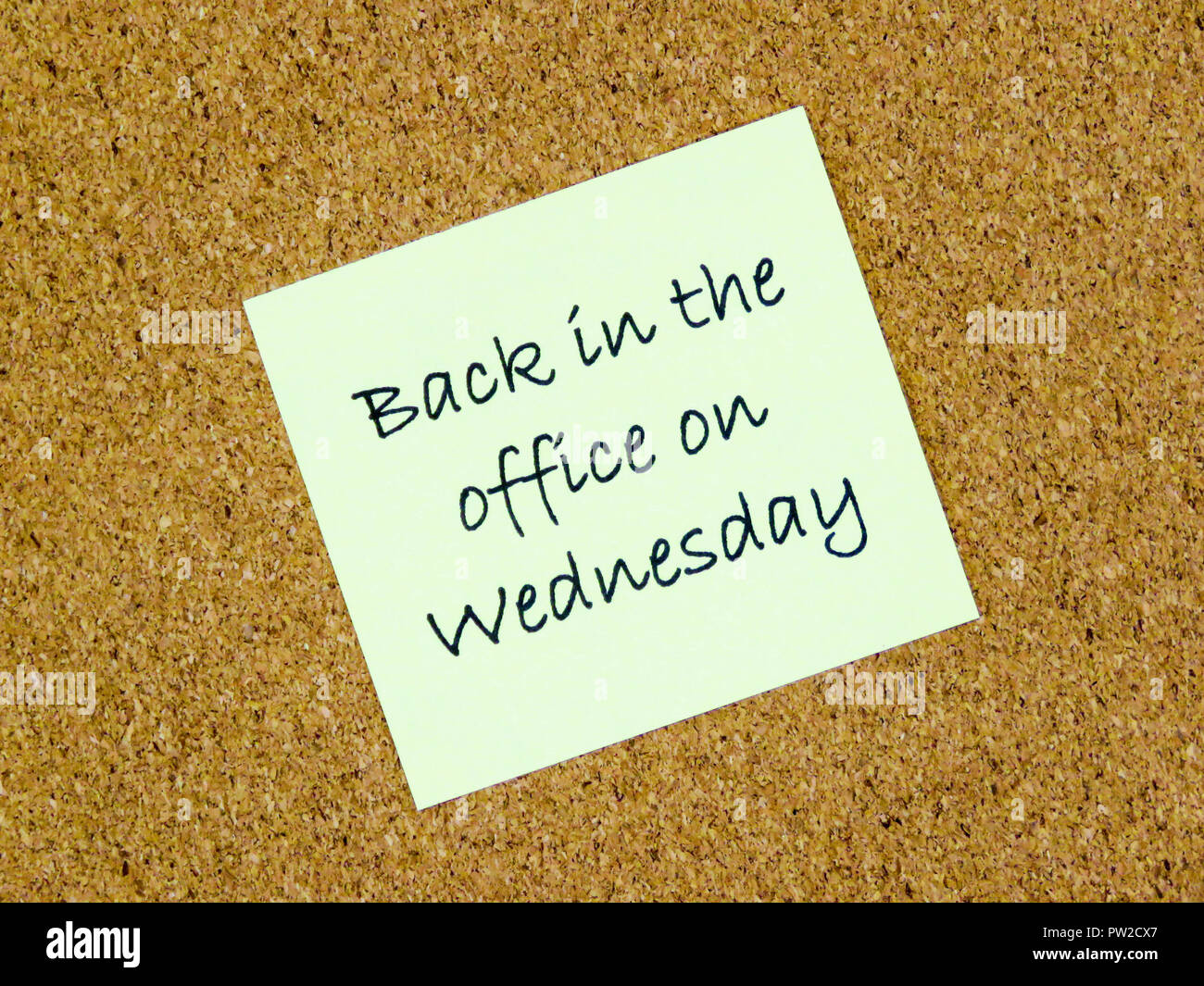 A yellow sticky note with back in the office on Wednesday written on it ...