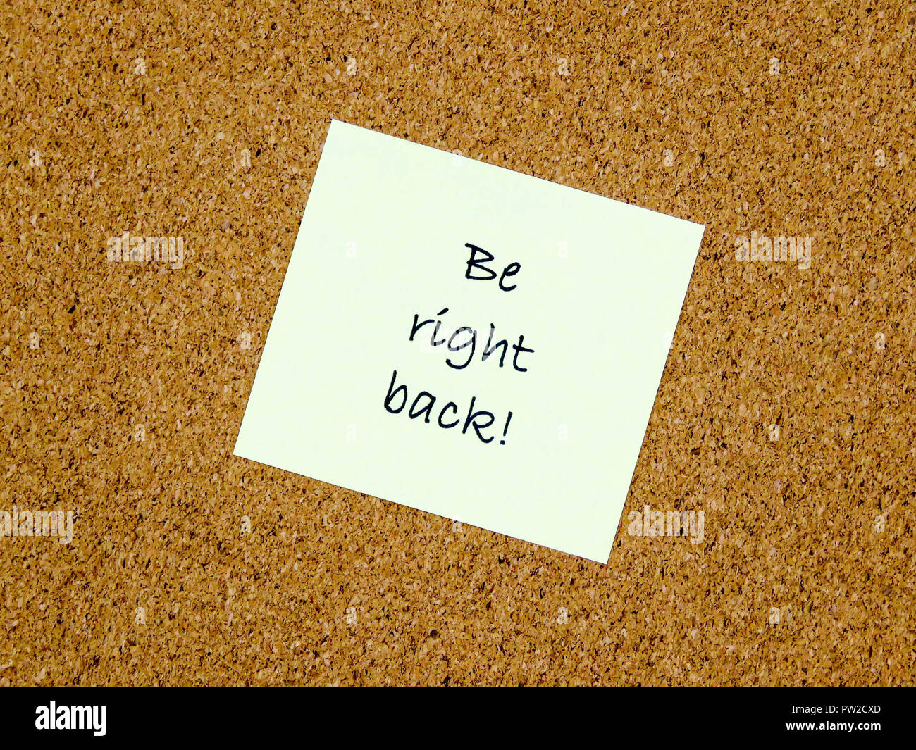 A yellow sticky note with be right back written on it on a cork board ...