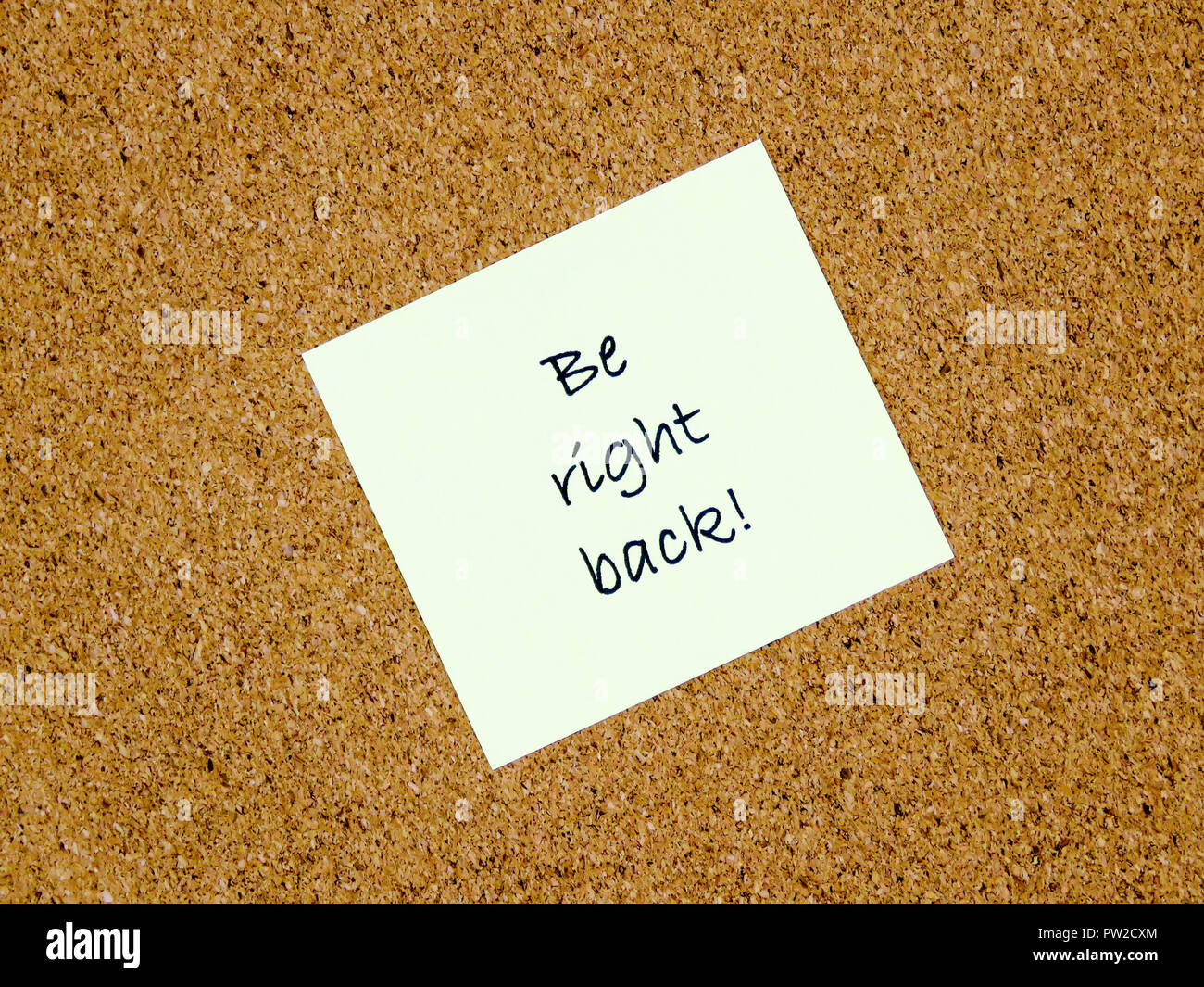 A yellow sticky note with be right back written on it on a cork board ...