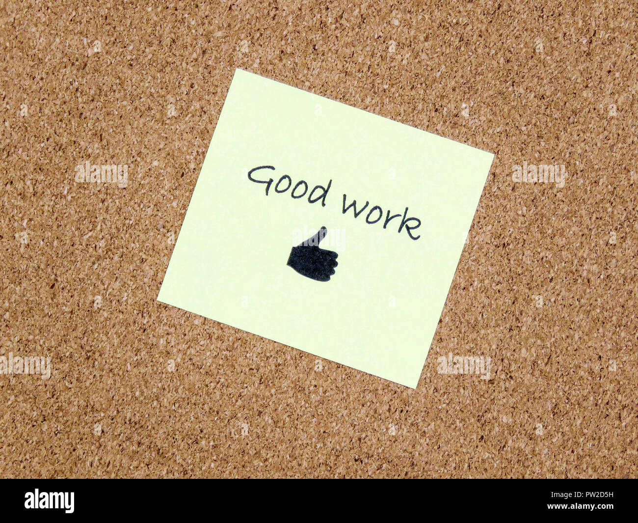 A yellow sticky note with good work written on it on a cork board ...