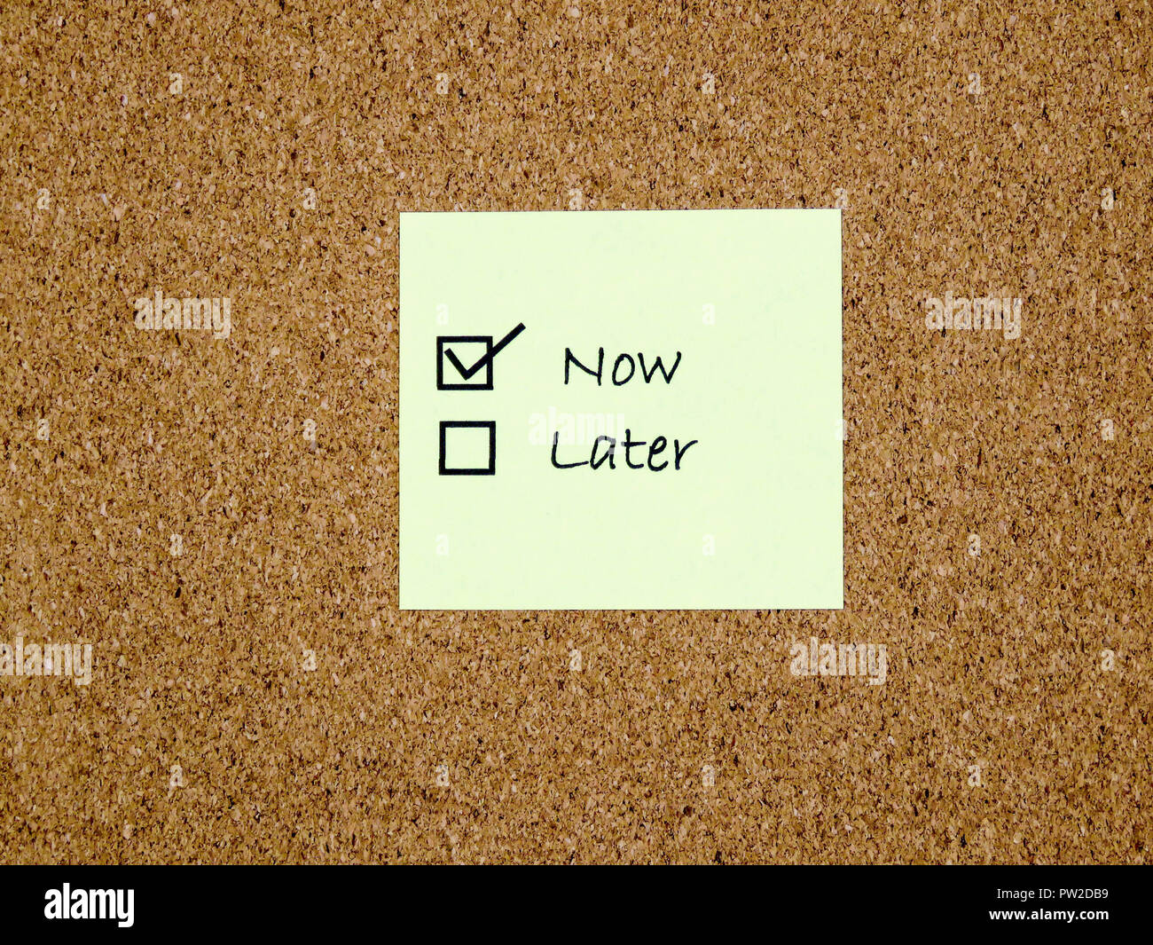 A yellow sticky note with now / later tick box written on it on a cork ...