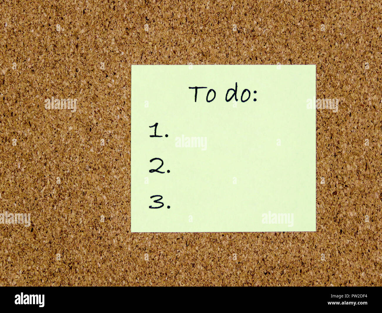 A yellow sticky note with to do list written on it on a cork board ...