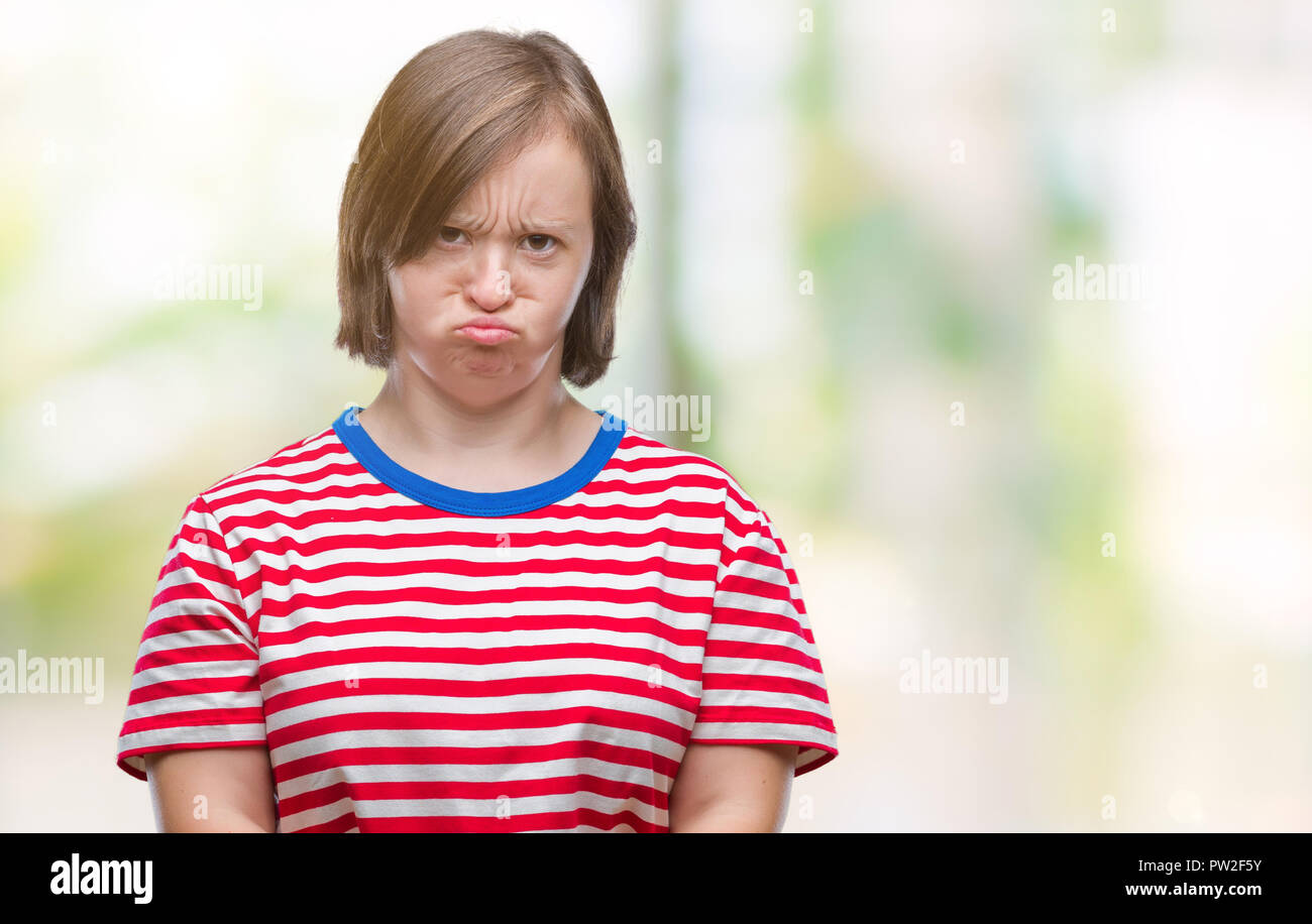 Young adult woman with down syndrome over isolated background depressed ...