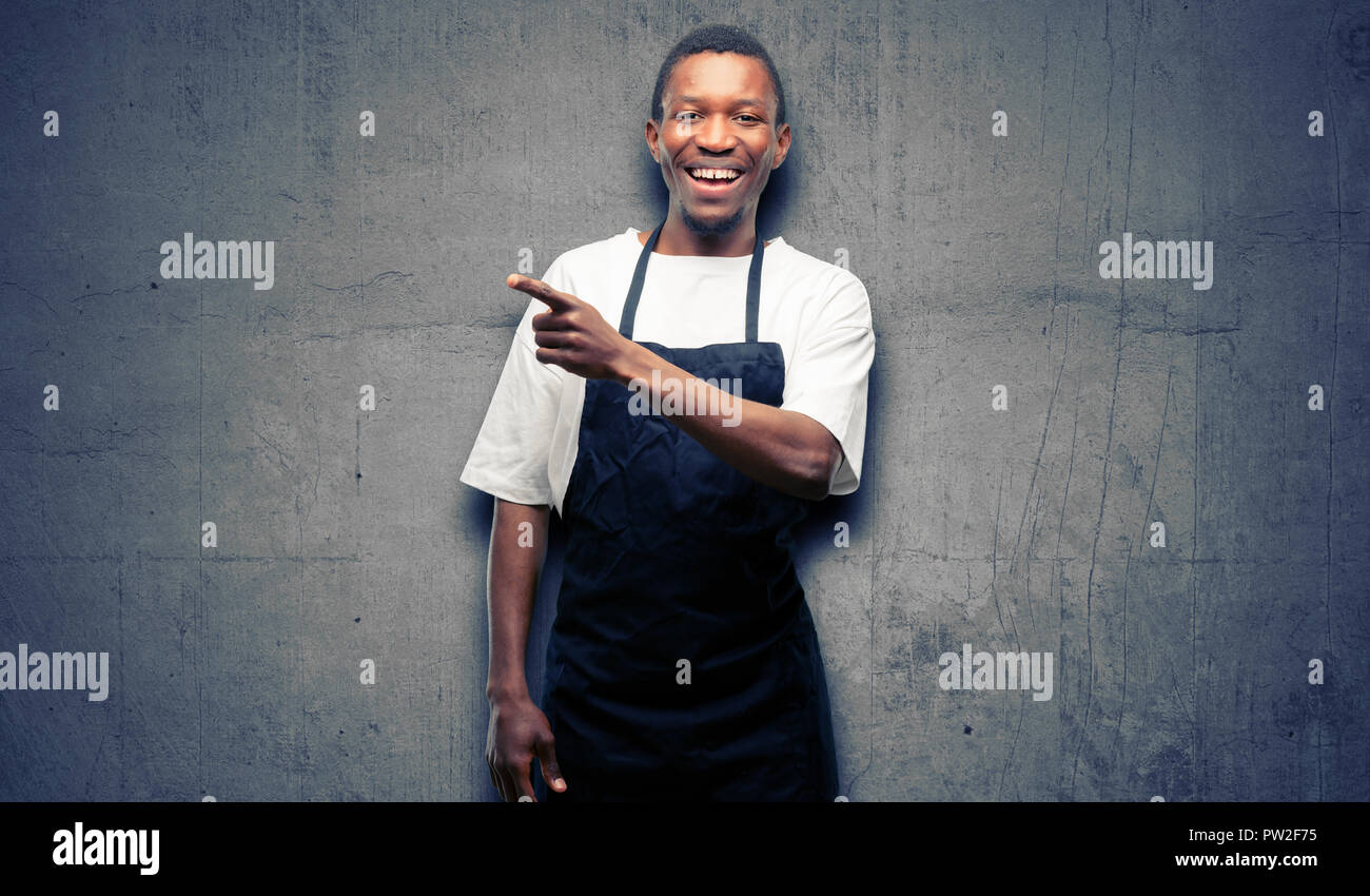 African man shop owner wearing apron pointing away side with finger ...