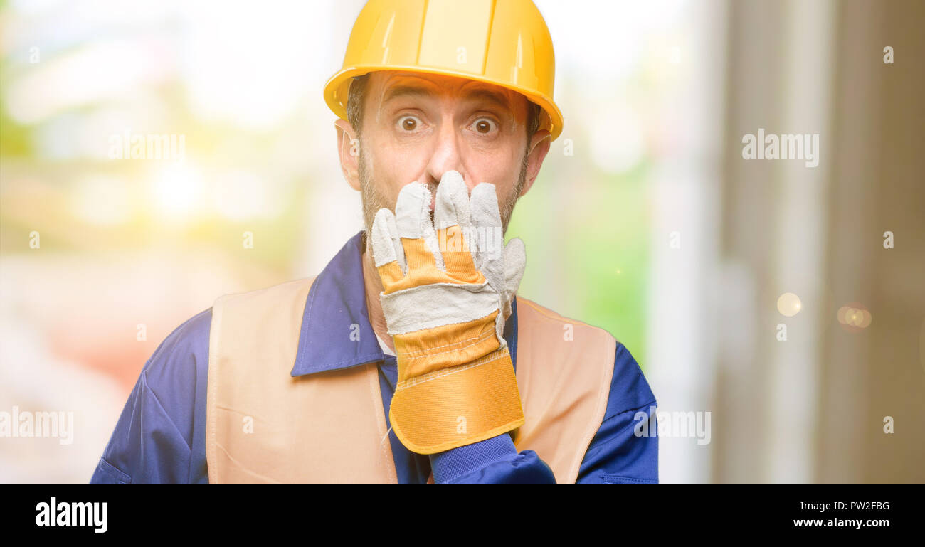 Senior engineer man, construction worker covers mouth in shock, looks ...