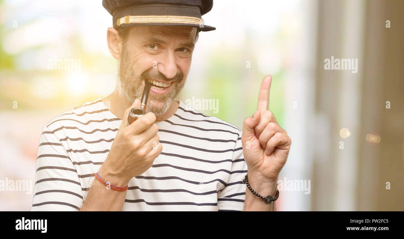 Sailor captain man smoking a tobacco pipe pointing away side with ...