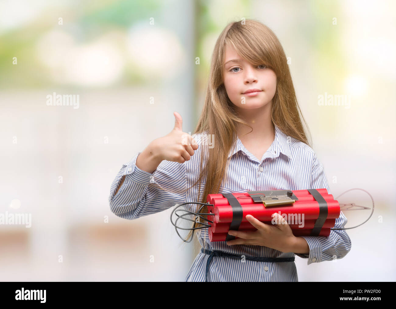 Young blonde child holding dynamite bomb happy with big smile doing ok ...