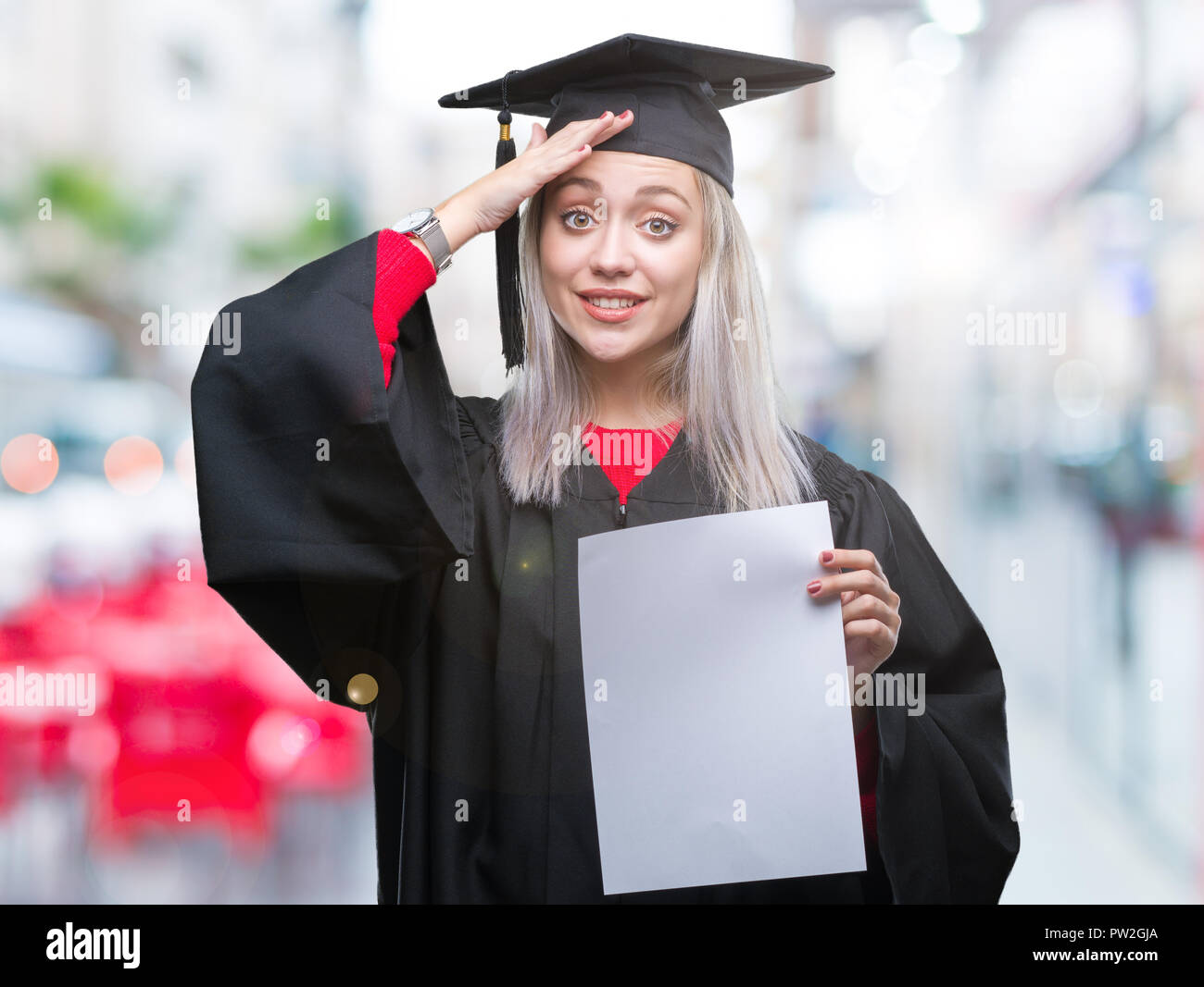 Young blonde woman wearing graduate uniform holding degree over ...