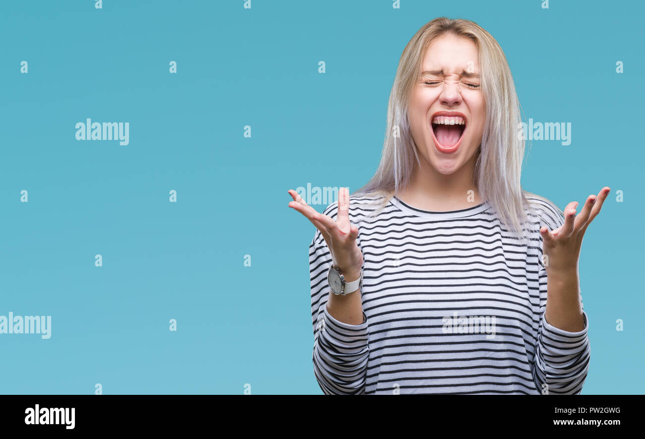 Young blonde woman over isolated background crazy and mad shouting and ...