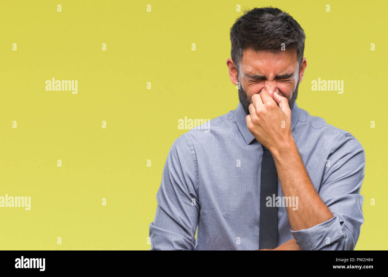Adult hispanic business man over isolated background smelling something ...