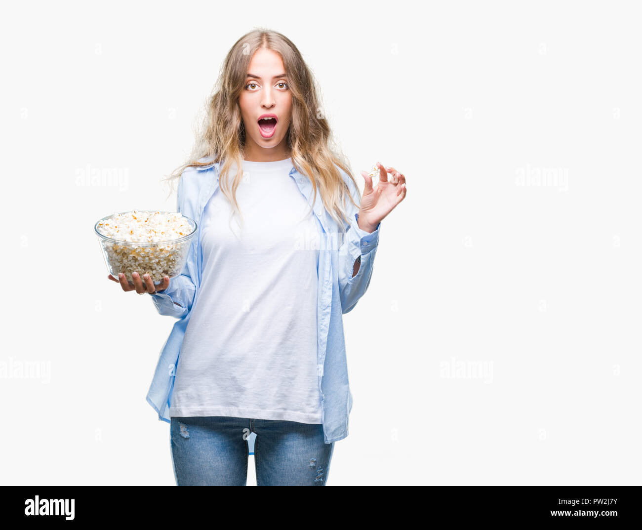 Beautiful young blonde woman eating popcorn over isolated background ...