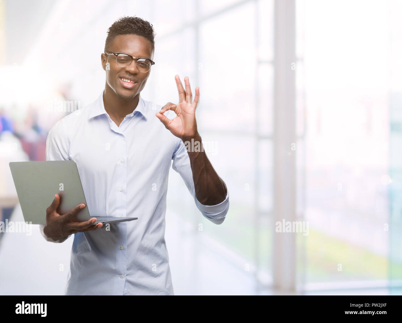 Young african american businessman using computer laptop doing ok sign ...