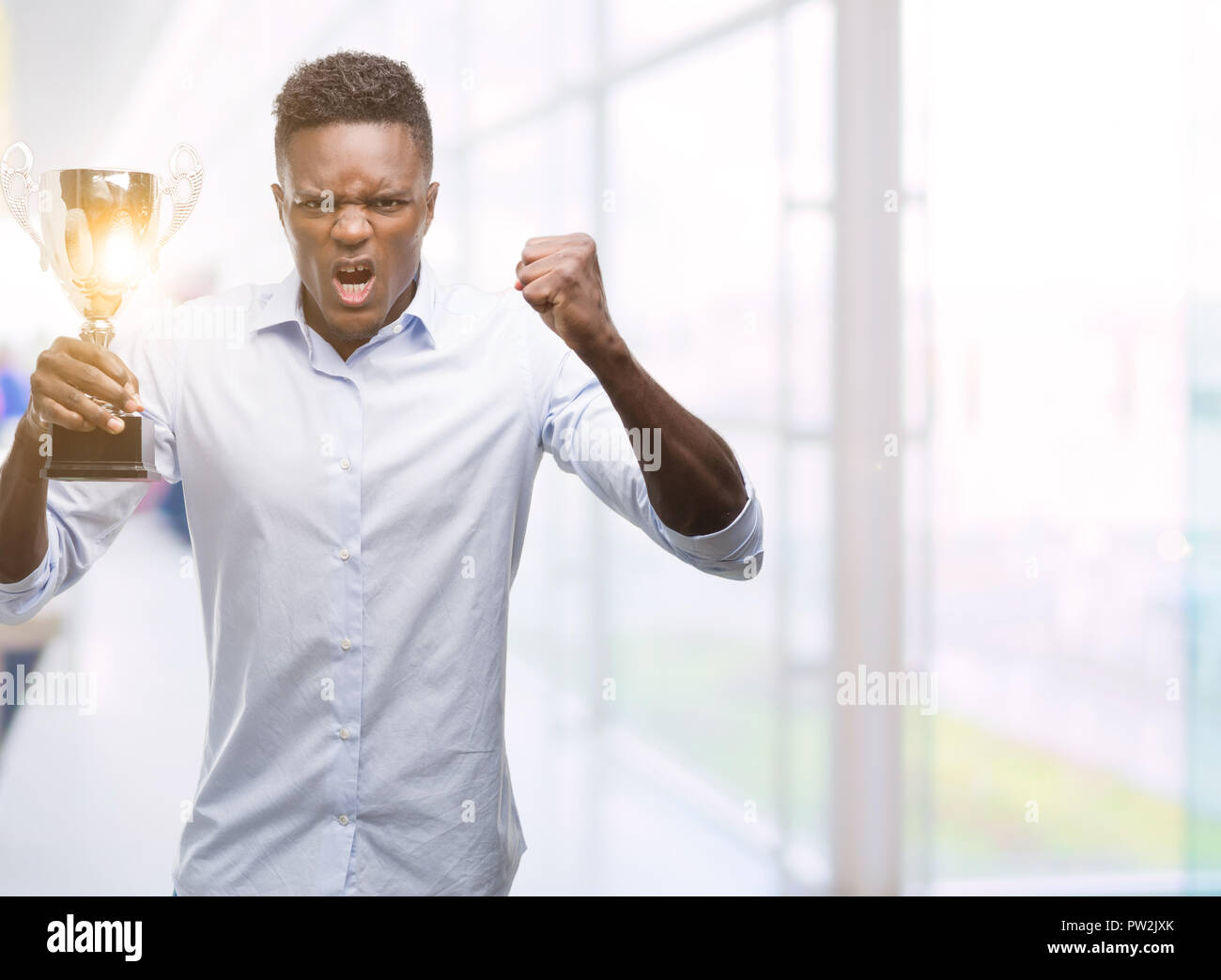 Young african american man holding trophy annoyed and frustrated ...