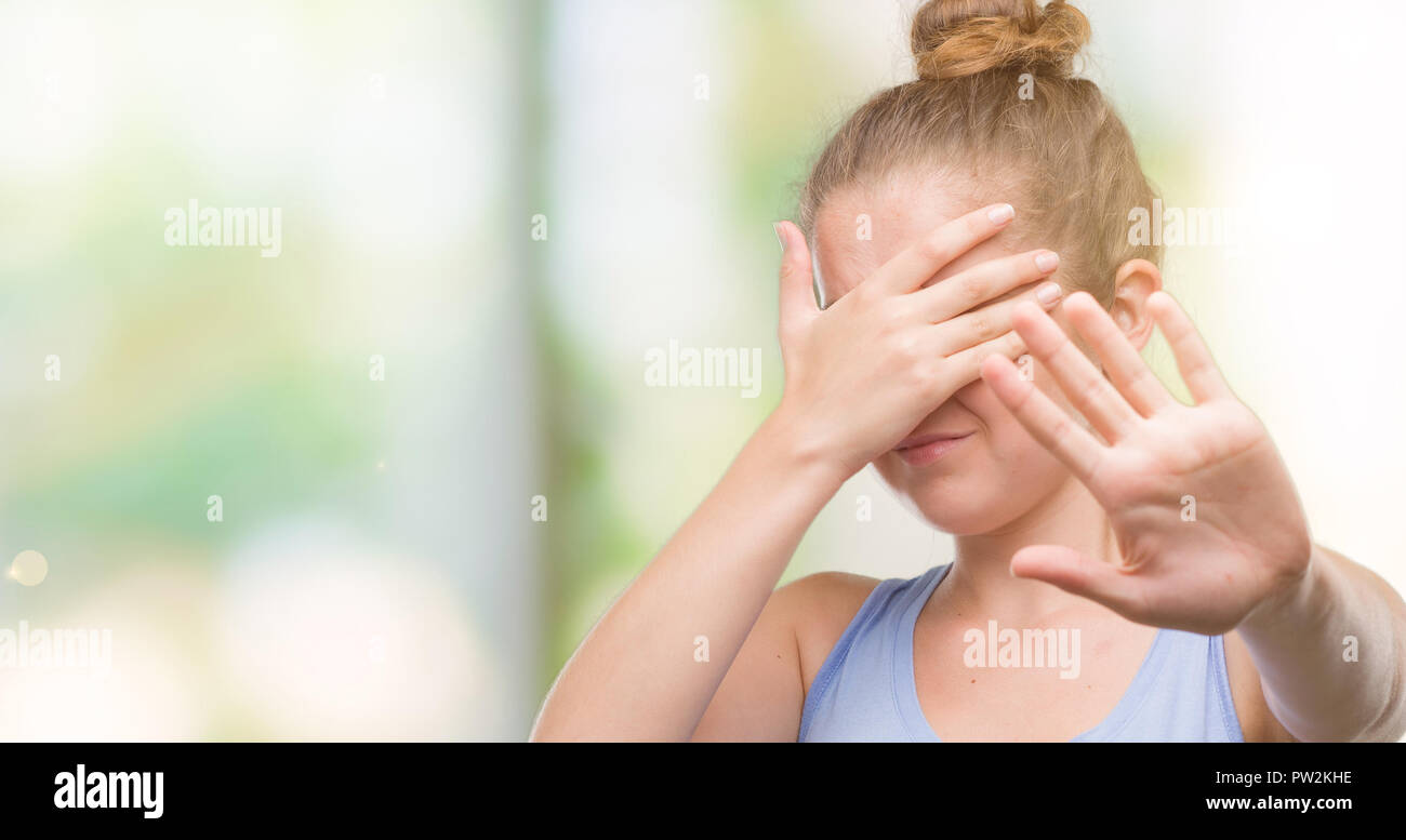 Young blonde woman covering eyes with hands and doing stop gesture with ...